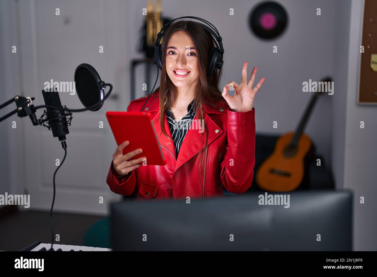Young brunette woman singing song using microphone doing ok sign with ...