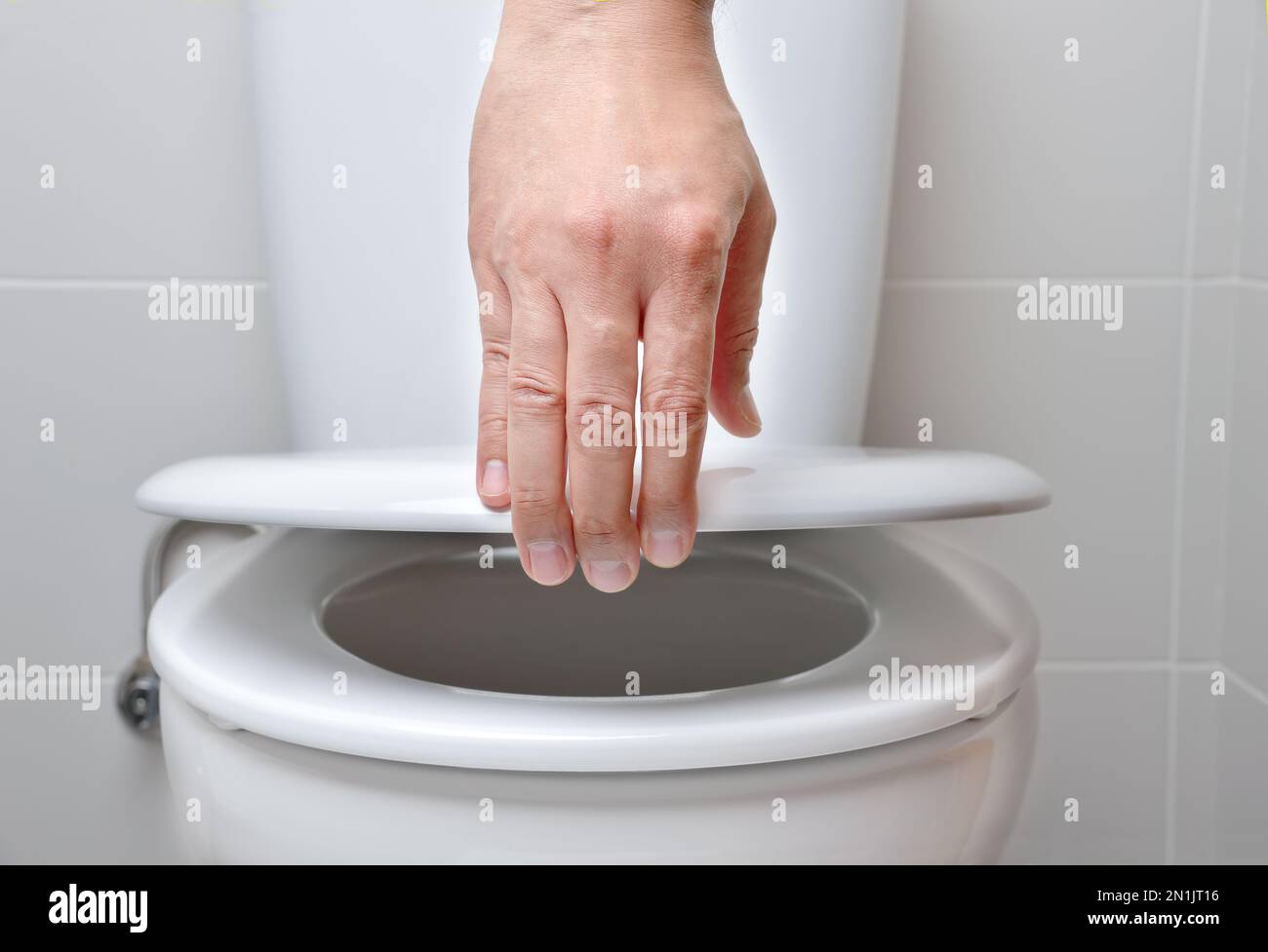 hand of a man closing the lid of a toilet Stock Photo - Alamy