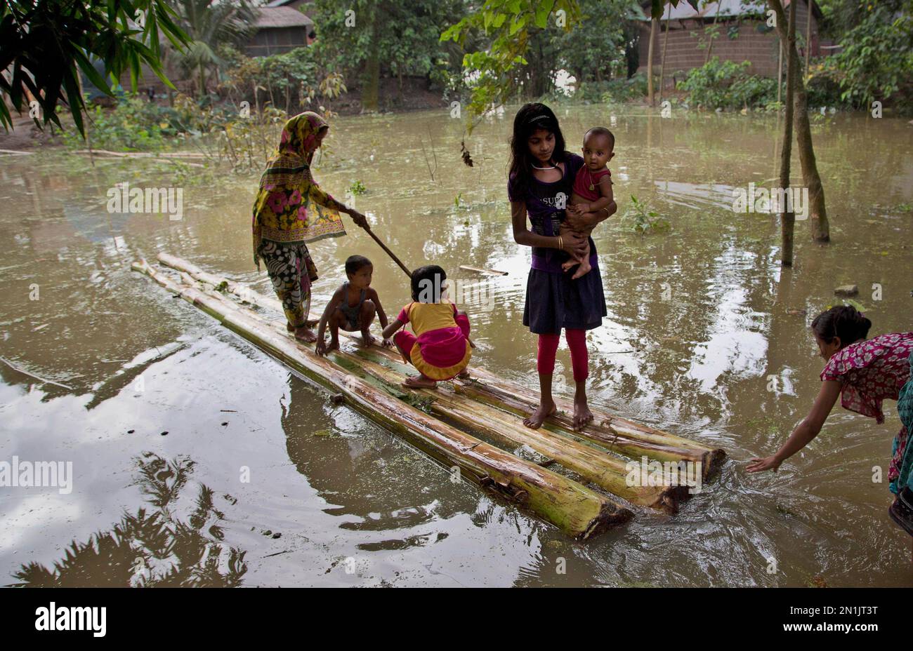 An Indian family prepare to cross floodwaters on a banana raft at ...