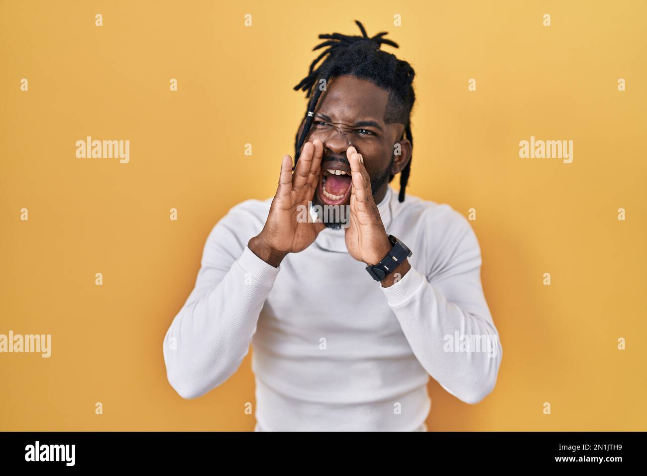 African man with dreadlocks wearing turtleneck sweater over yellow ...