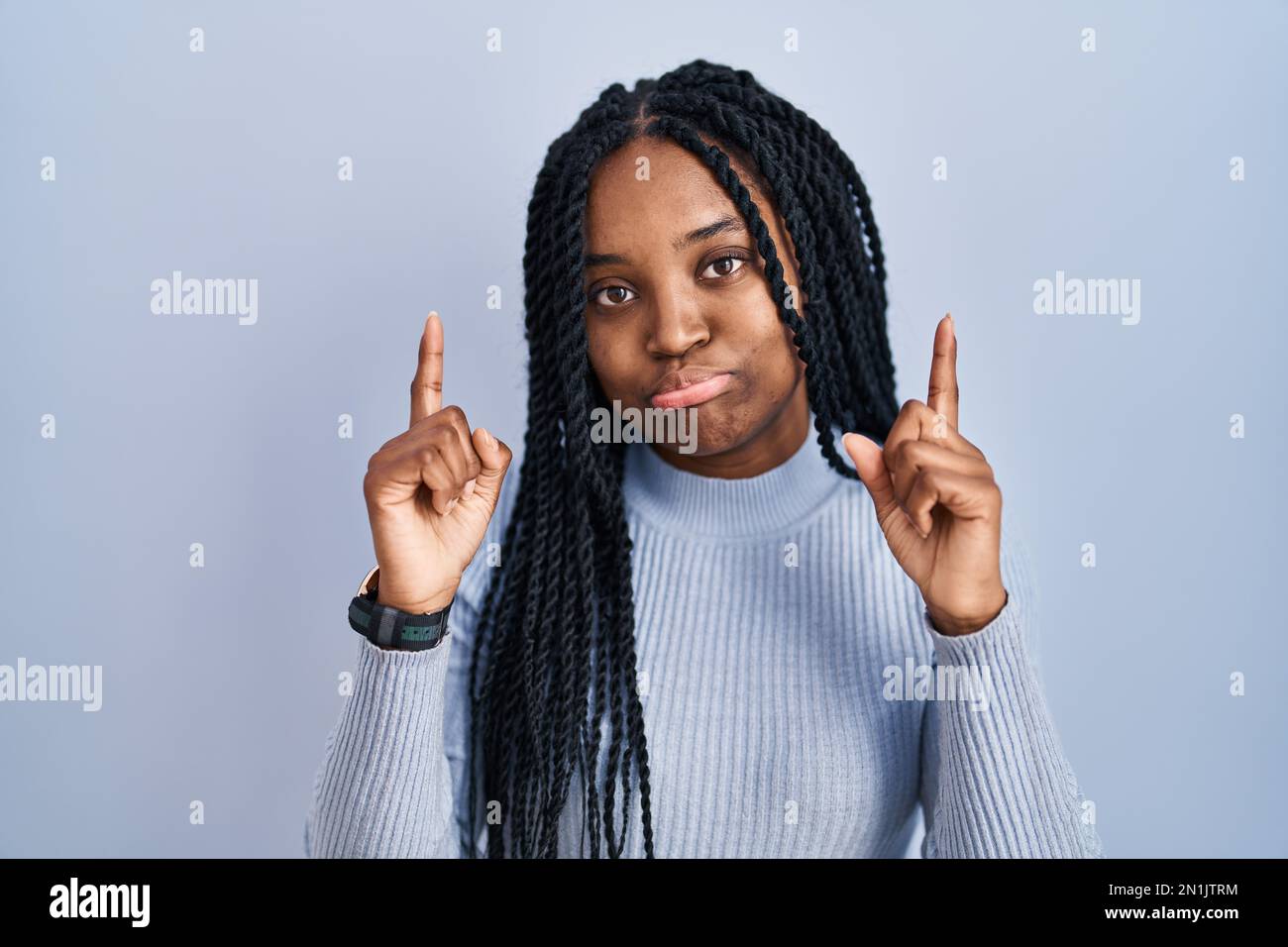 African american woman standing over blue background pointing up ...