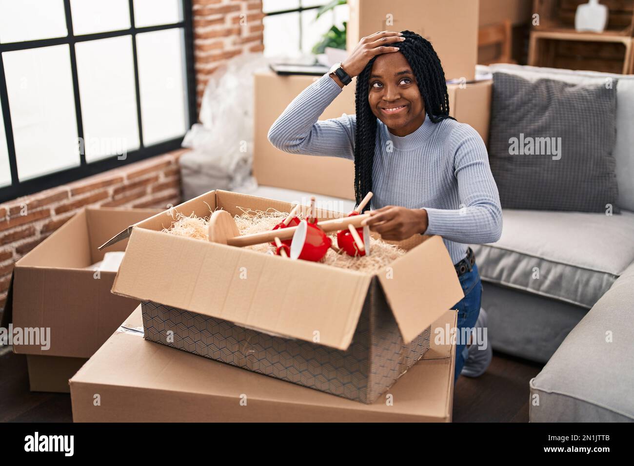 African american woman moving to a new home opening boxes stressed and ...