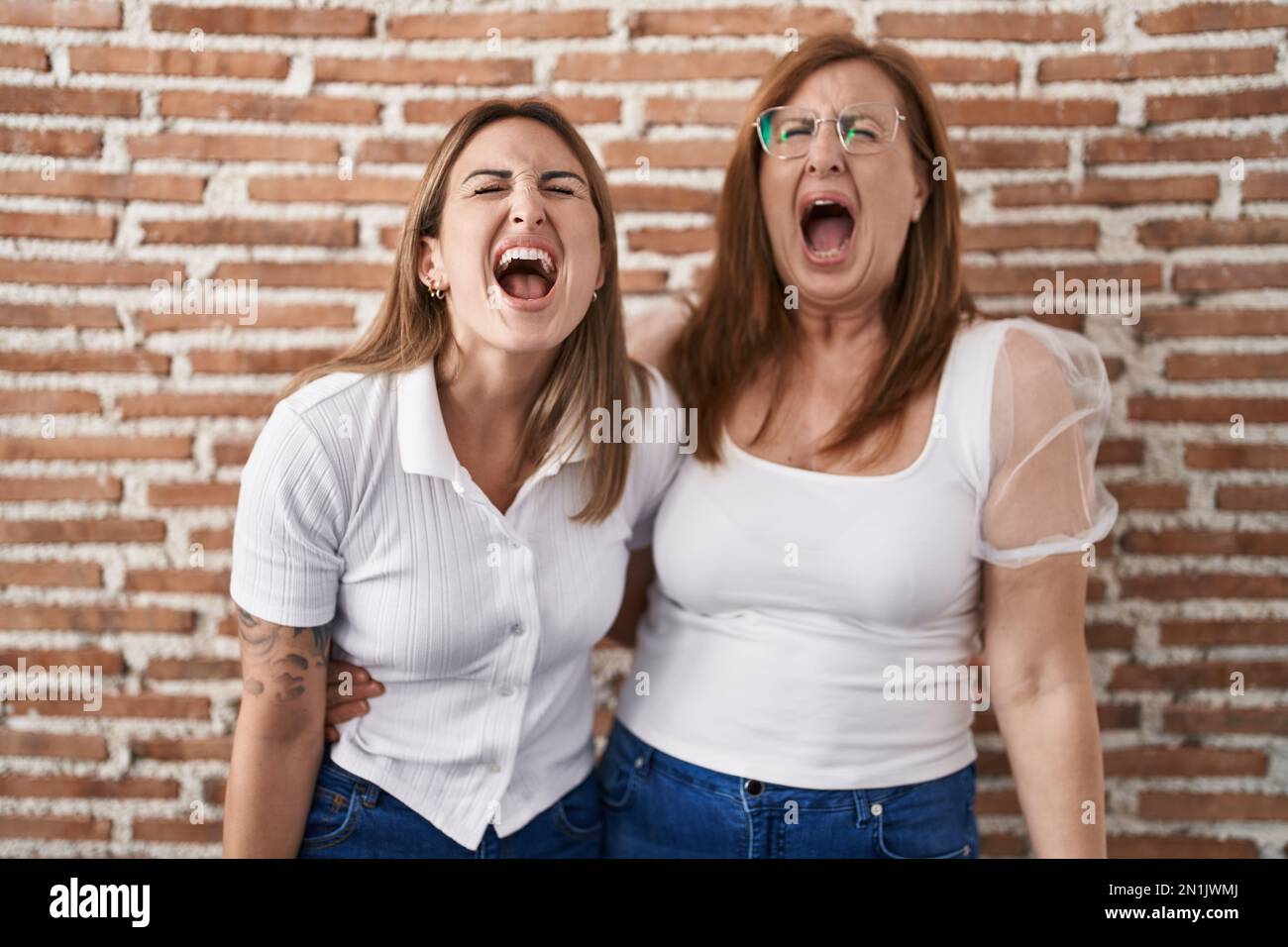 Hispanic mother and daughter wearing casual white t shirt angry and mad ...