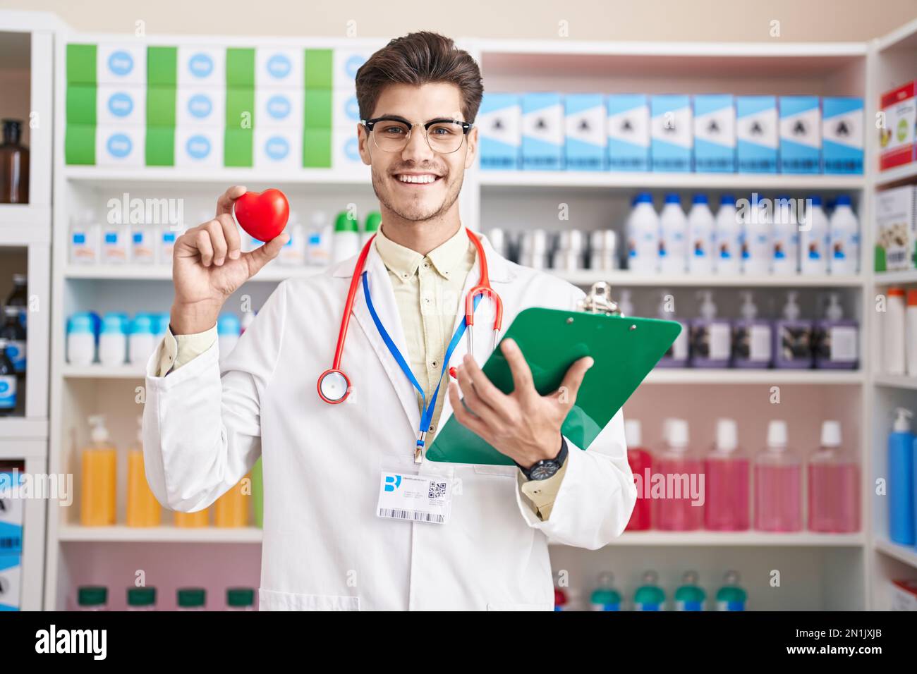 Young hispanic man working at pharmacy drugstore holding heart smiling ...
