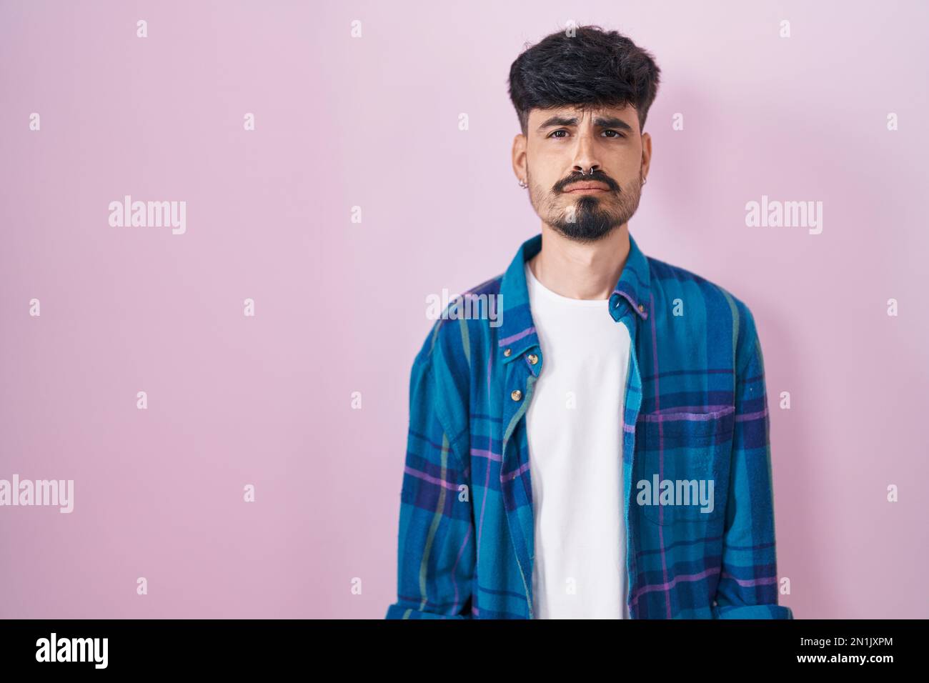 Young hispanic man with beard standing over pink background depressed ...