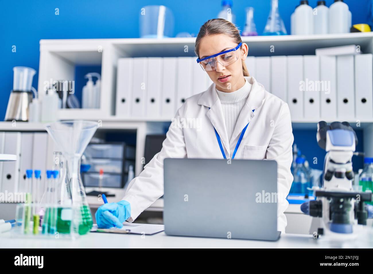 Young woman scientist writing on clipboard at laboratory Stock Photo - Alamy