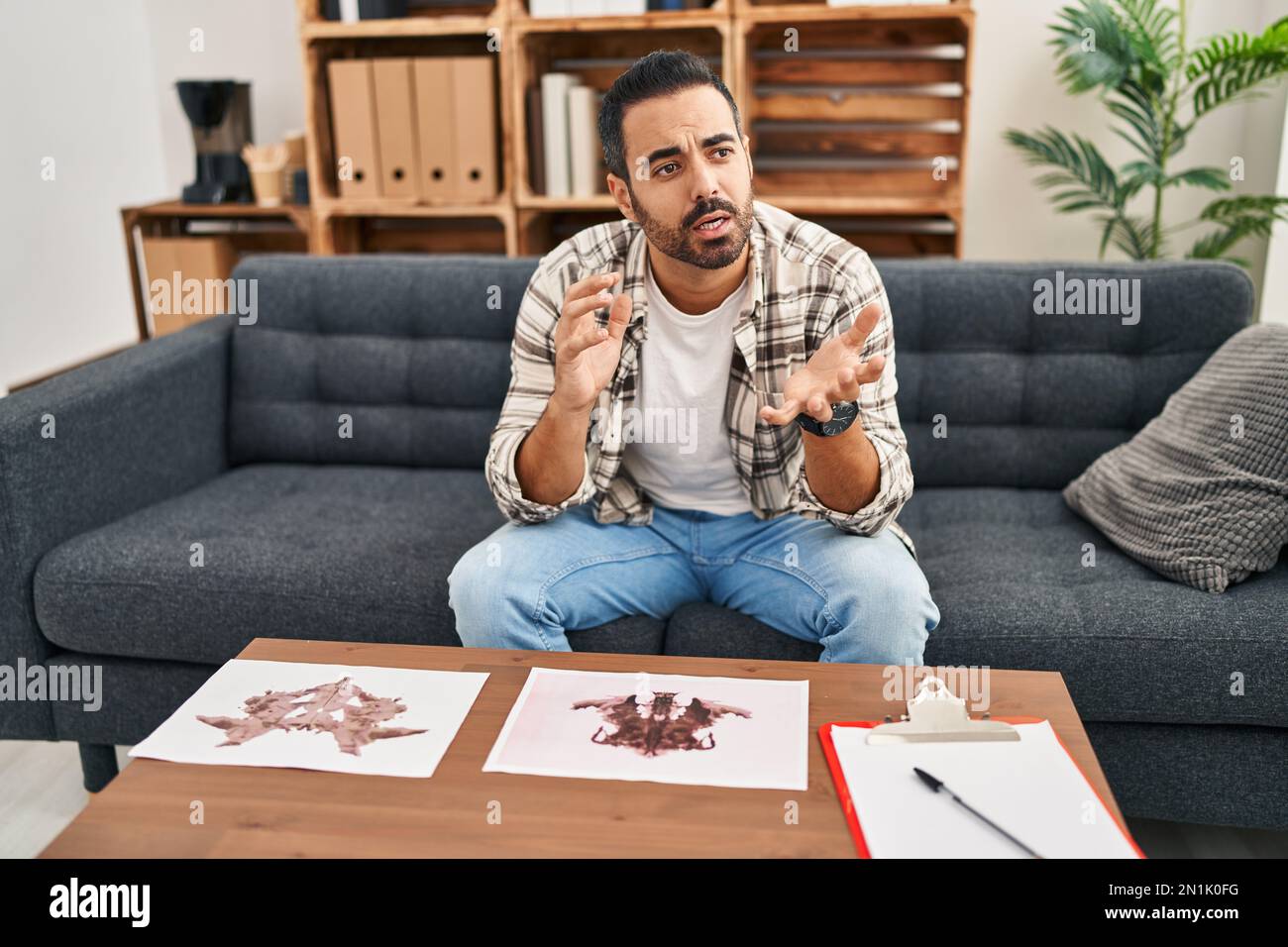 Young hispanic man patient having rorschach test at psychology center ...