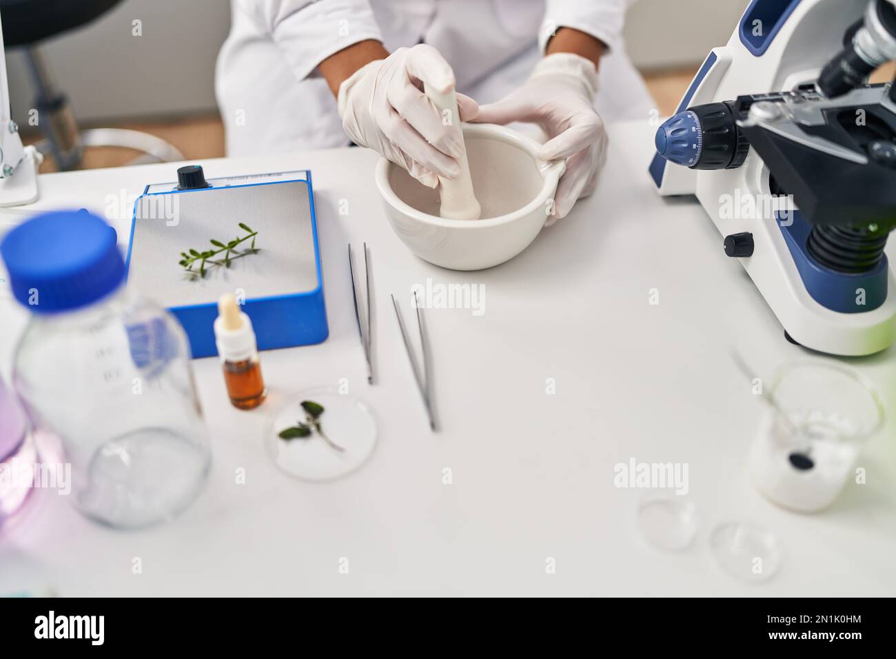 Young beautiful hispanic woman scientist mixing sample at laboratory ...