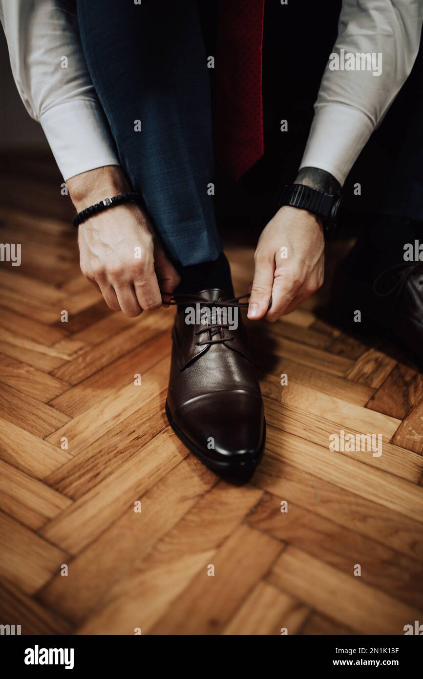 A vertical closeup of a man tying up his shoelaces of his shoes Stock ...
