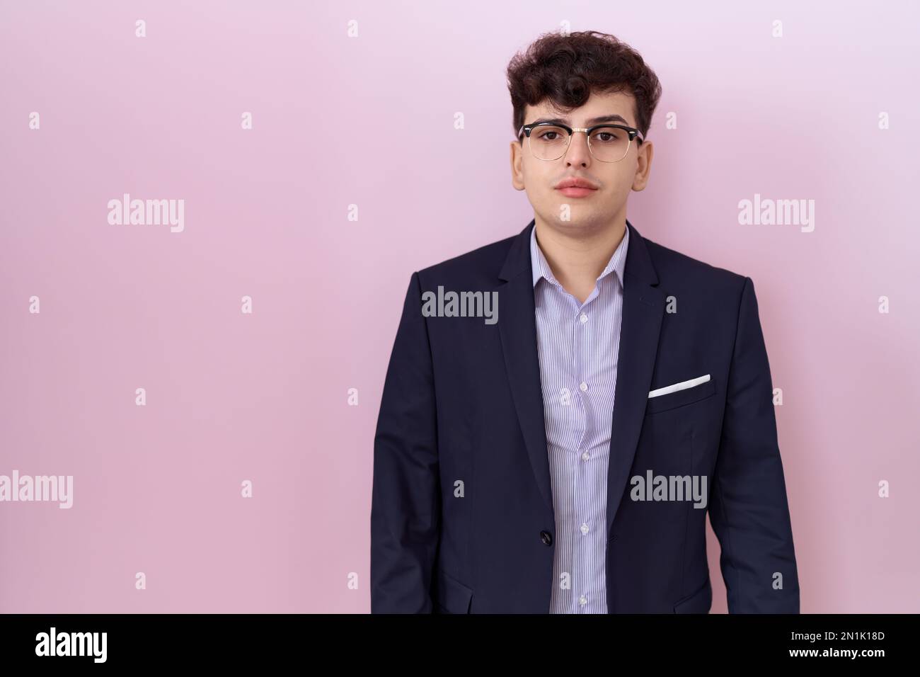 Young non binary man with beard wearing suit and tie relaxed with ...