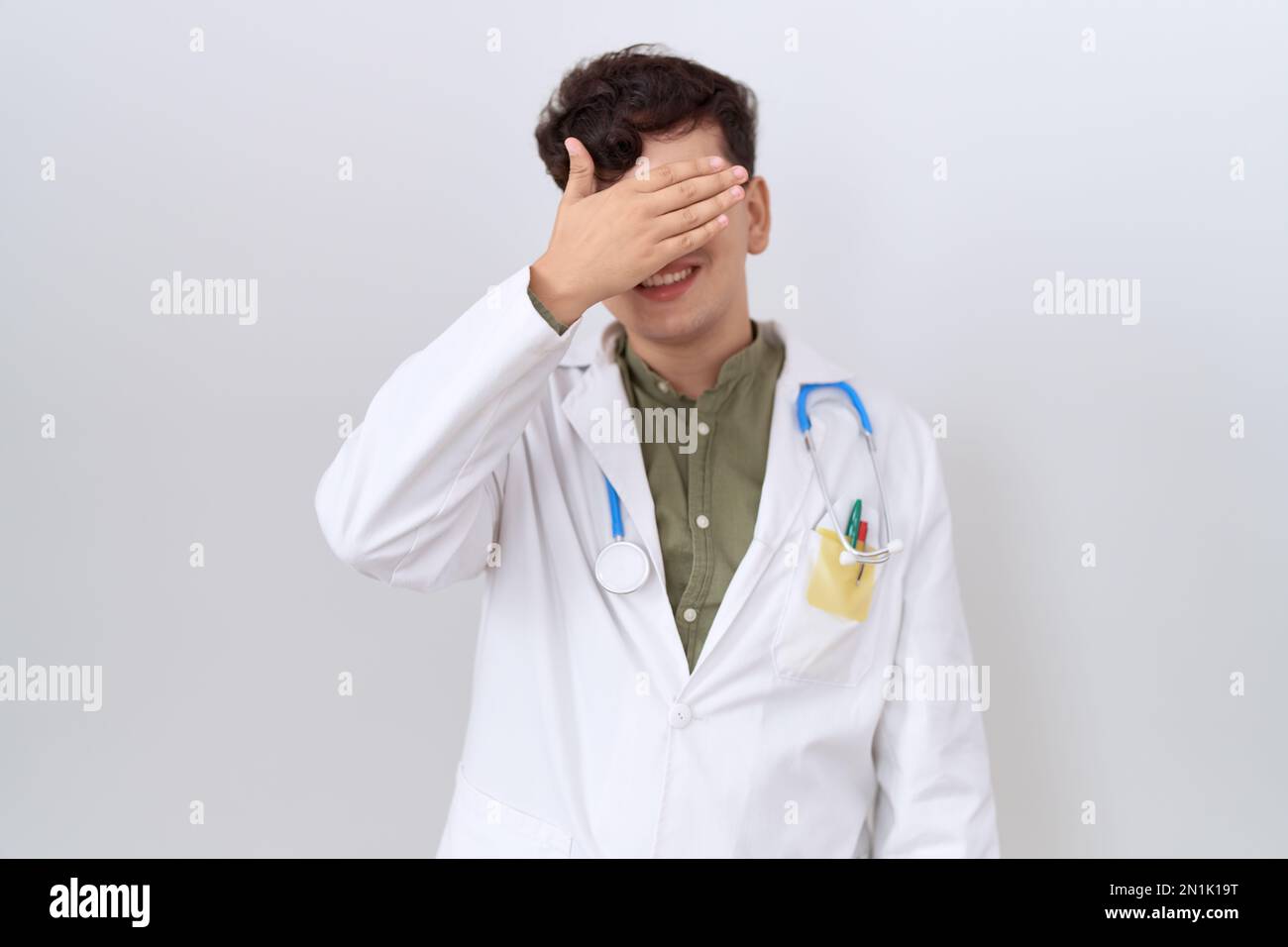 Young non binary man wearing doctor uniform and stethoscope smiling and ...