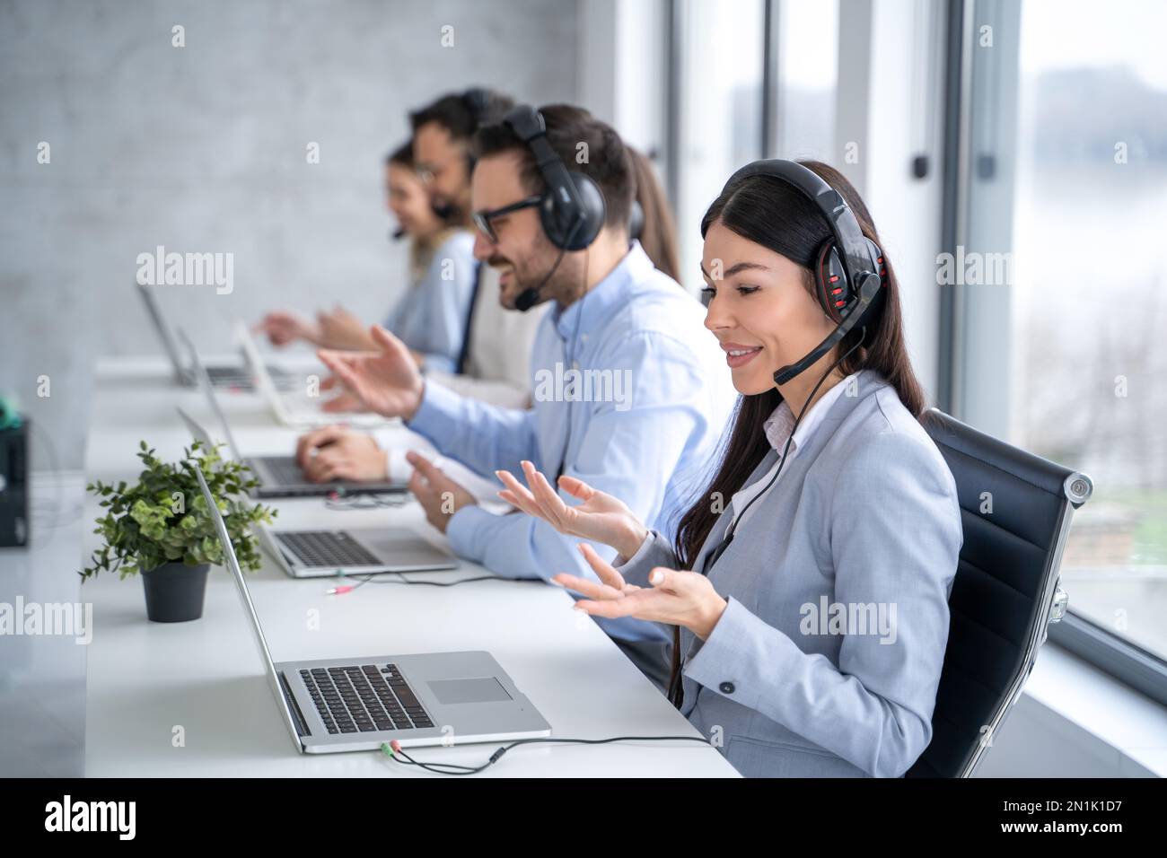 Portrait of friendly young female call center operator in headphones ...