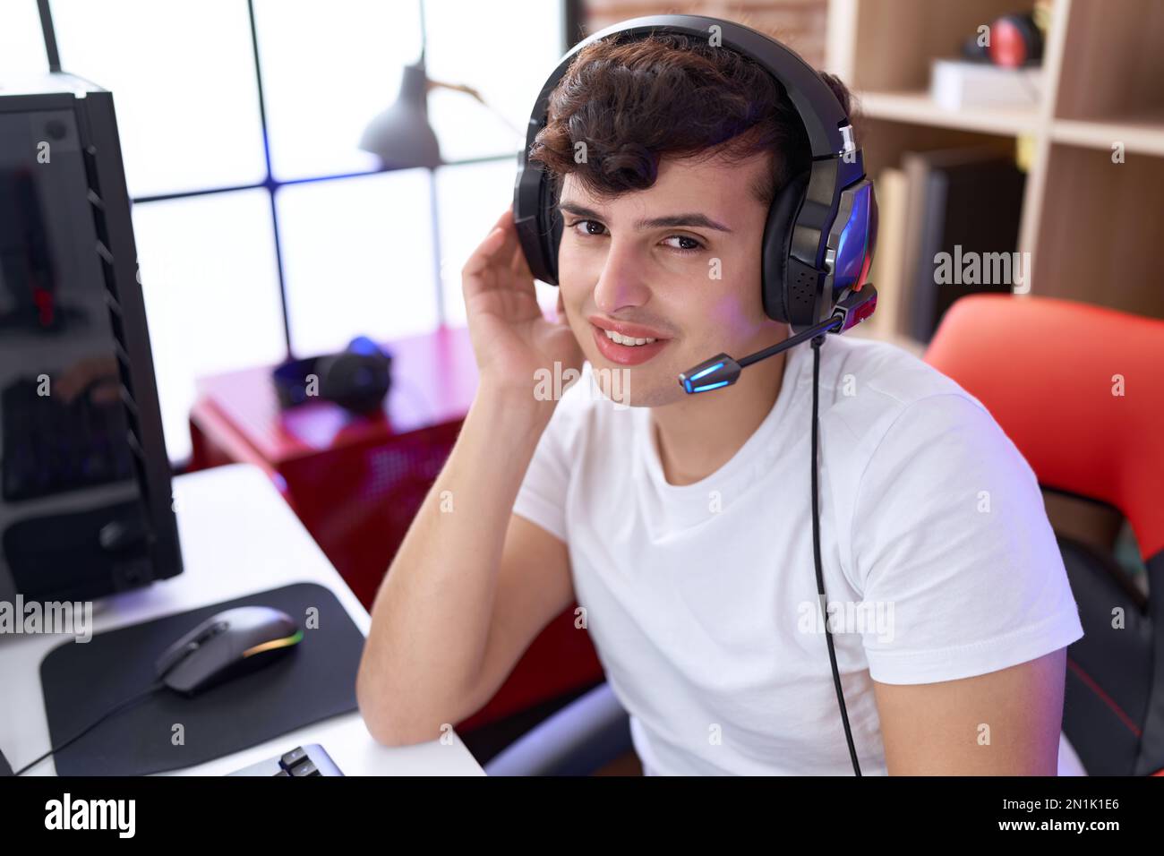 Non binary man streamer playing video game using computer at gaming ...