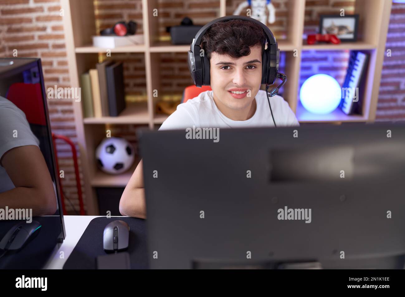 Non binary man streamer playing video game using computer at gaming ...