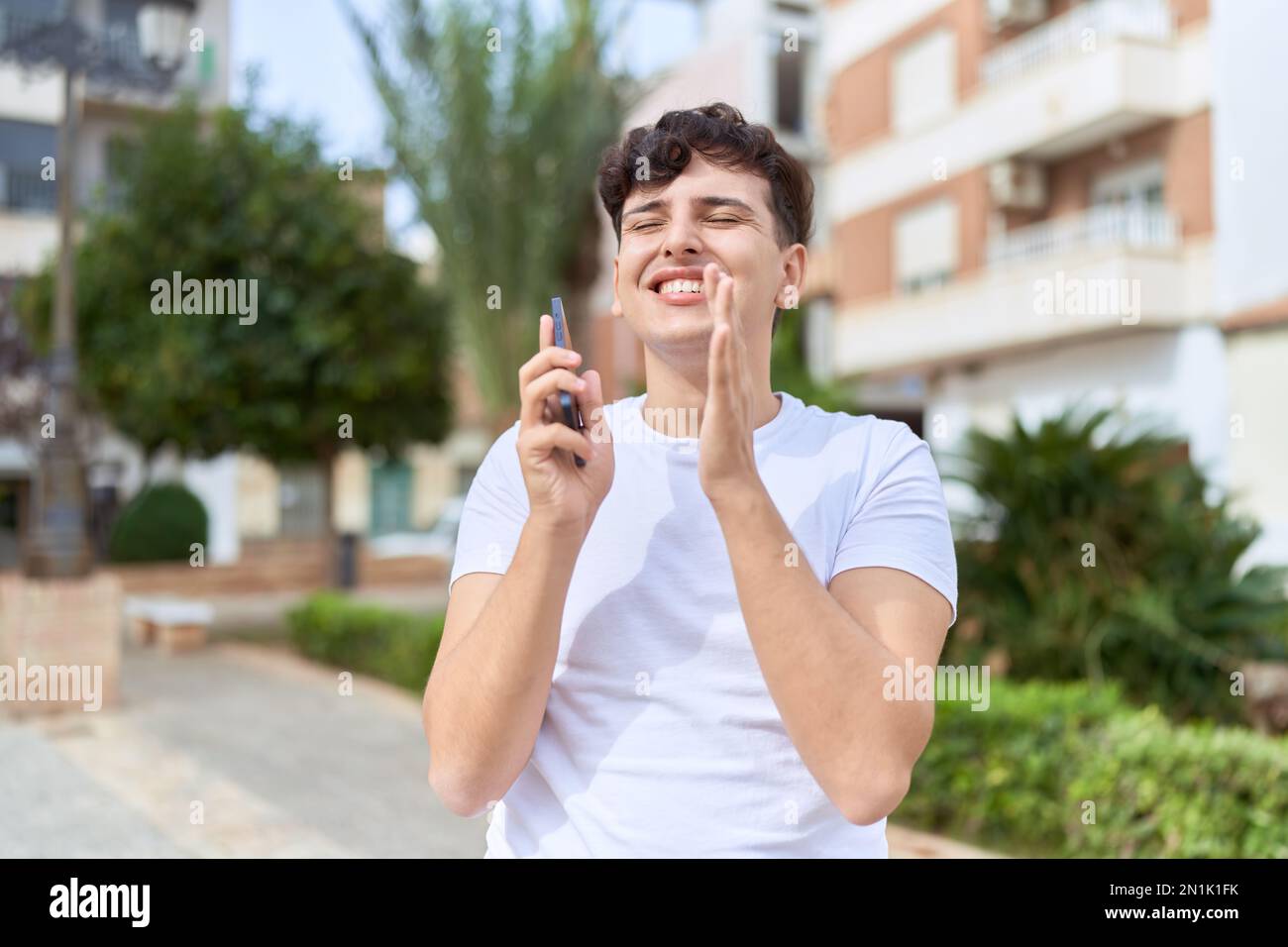 Non binary man using smartphone with winner expression at park Stock ...