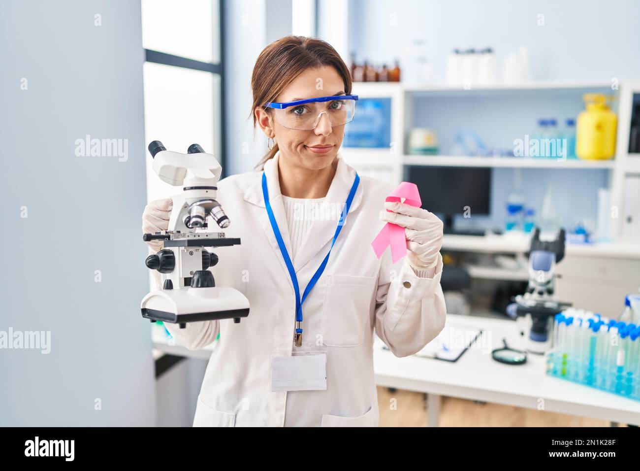 Young brunette woman working at scientist laboratory holding pink ...