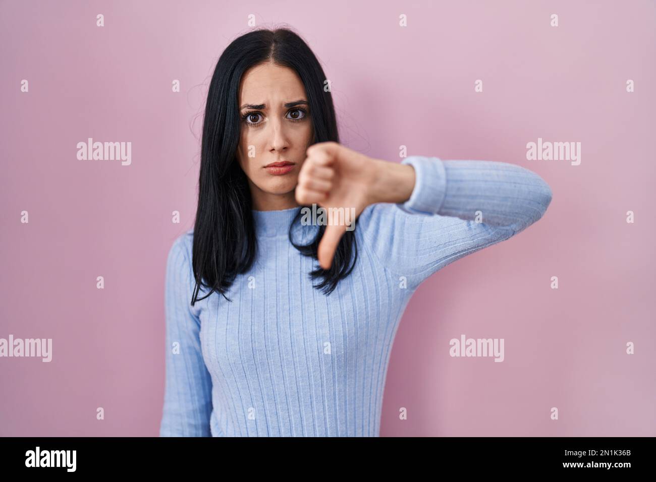 Hispanic woman standing over pink background looking unhappy and angry ...