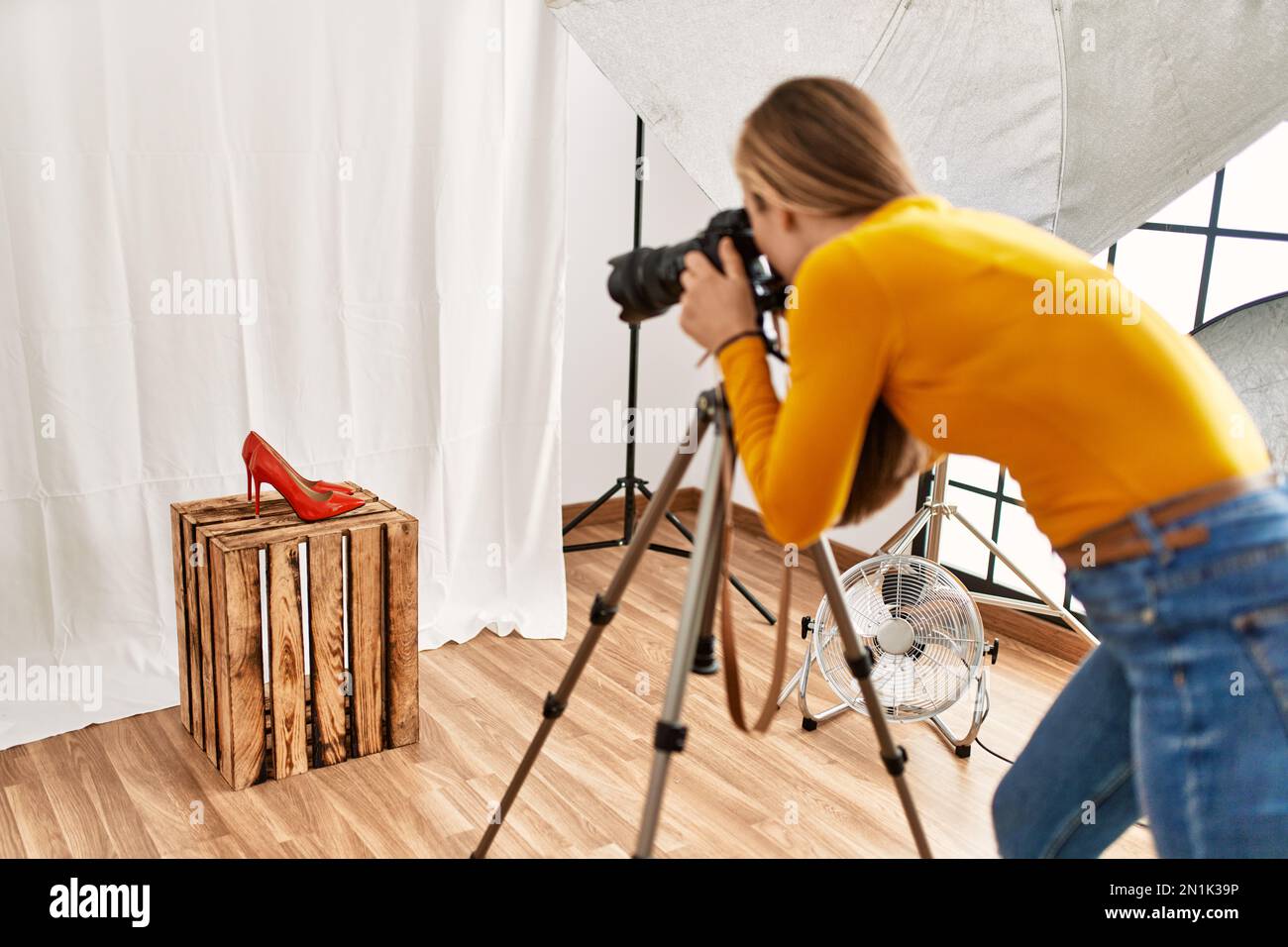 Young caucasian woman photographer making photo to high heel shoe at ...