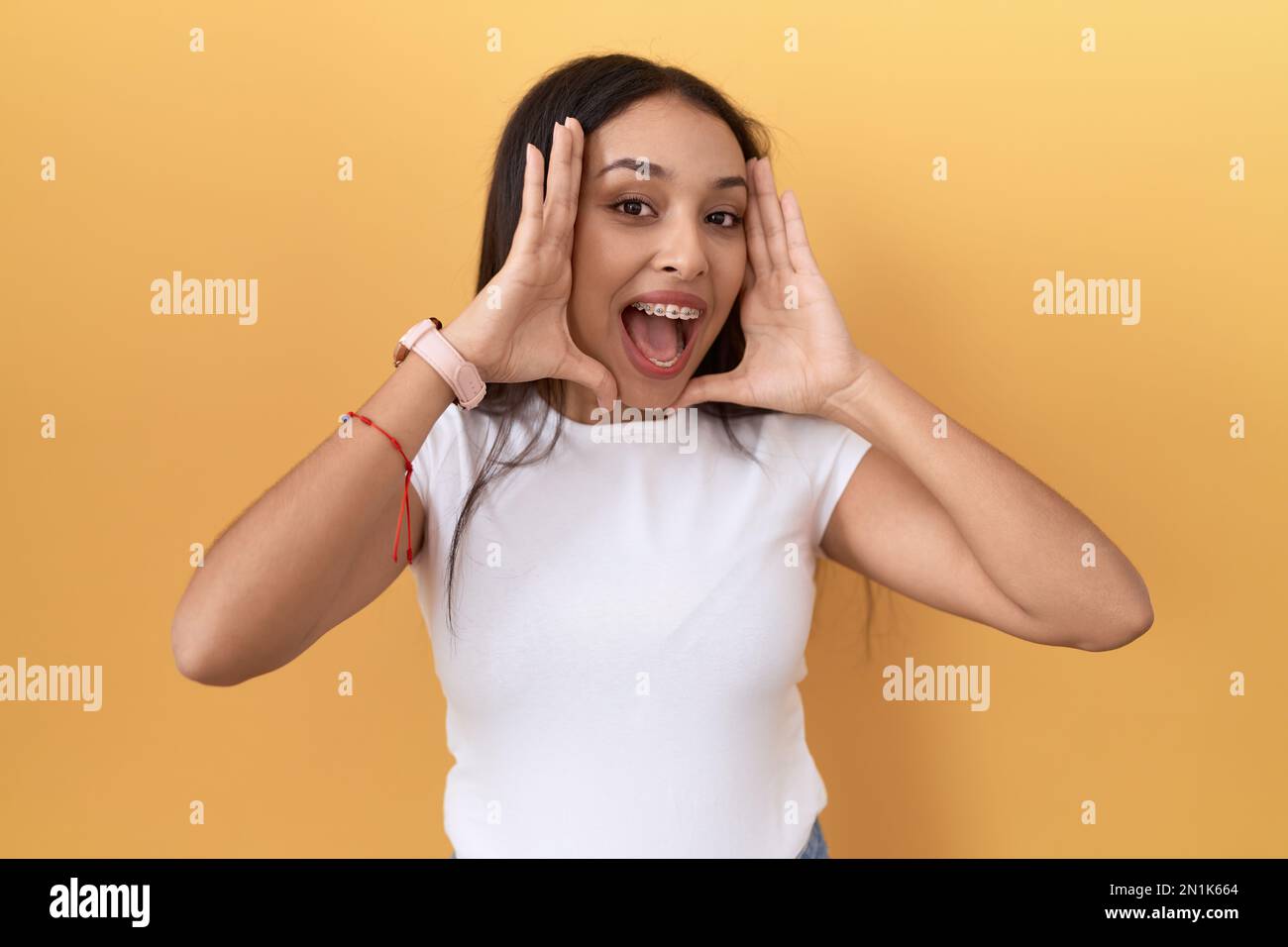 Young arab woman wearing casual white t shirt over yellow background ...