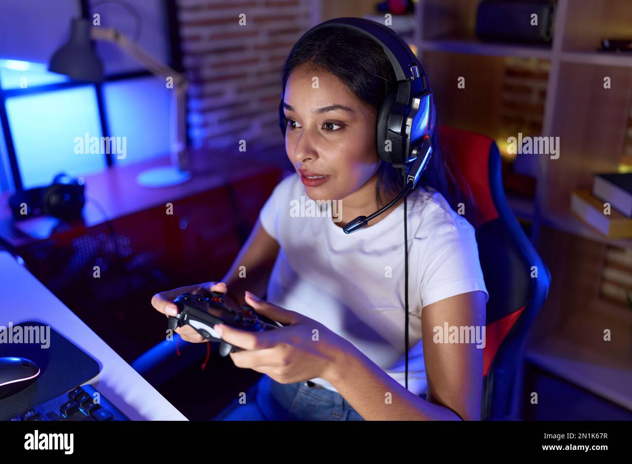 Young arab woman streamer playing video game using joystick at gaming ...