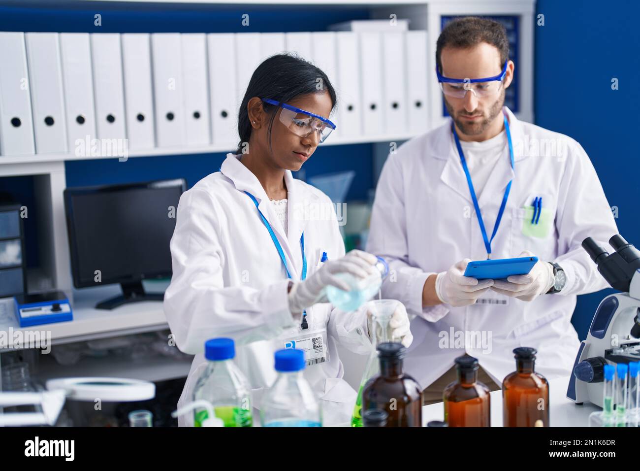 Man and woman scientists using touchpad measuring liquid at laboratory Stock Photo - Alamy