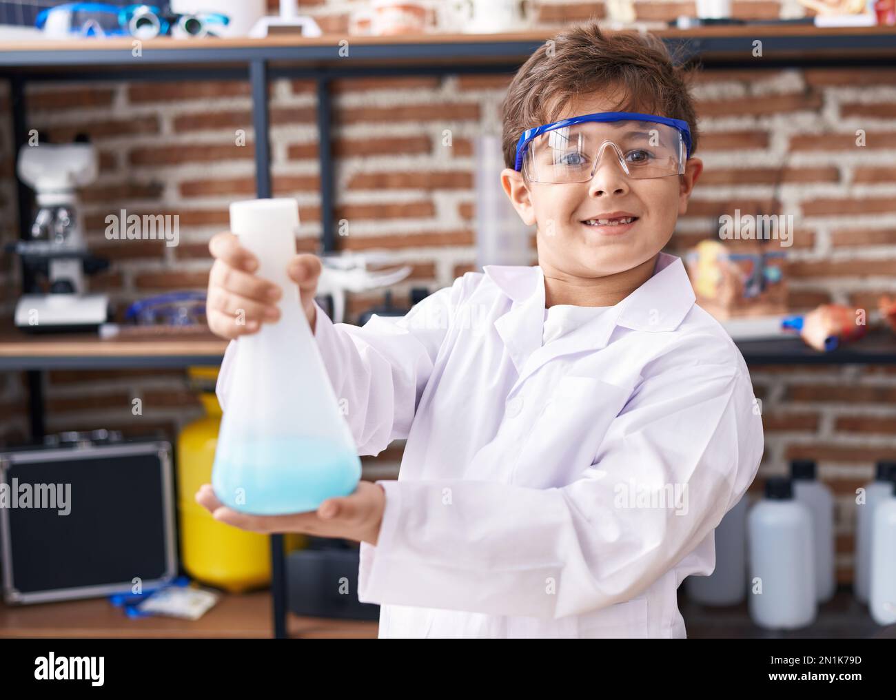 Adorable hispanic boy student smiling confident holding test tube at ...