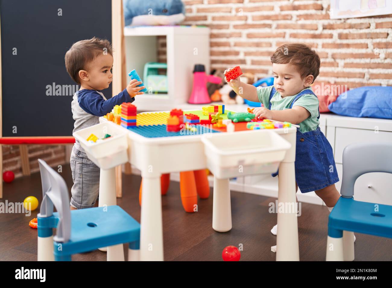 Two kids playing with construction blocks standing at kindergarten ...