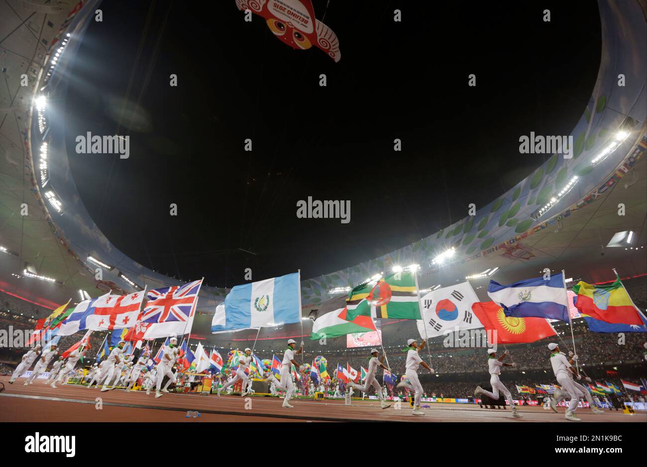 Performers carry the flags of competing nations during the closing ...
