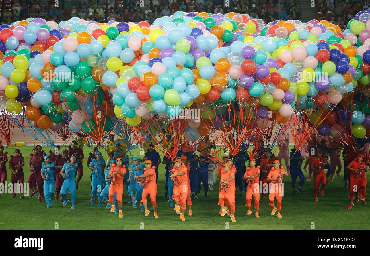 Performers run into the arena with balloons during the closing ceremony ...