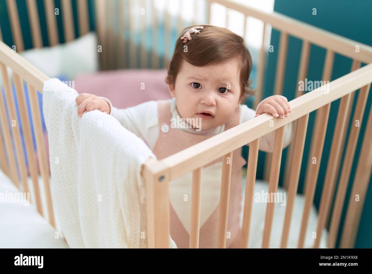 Adorable toddler standing on cradle with relaxed expression at bedroom ...