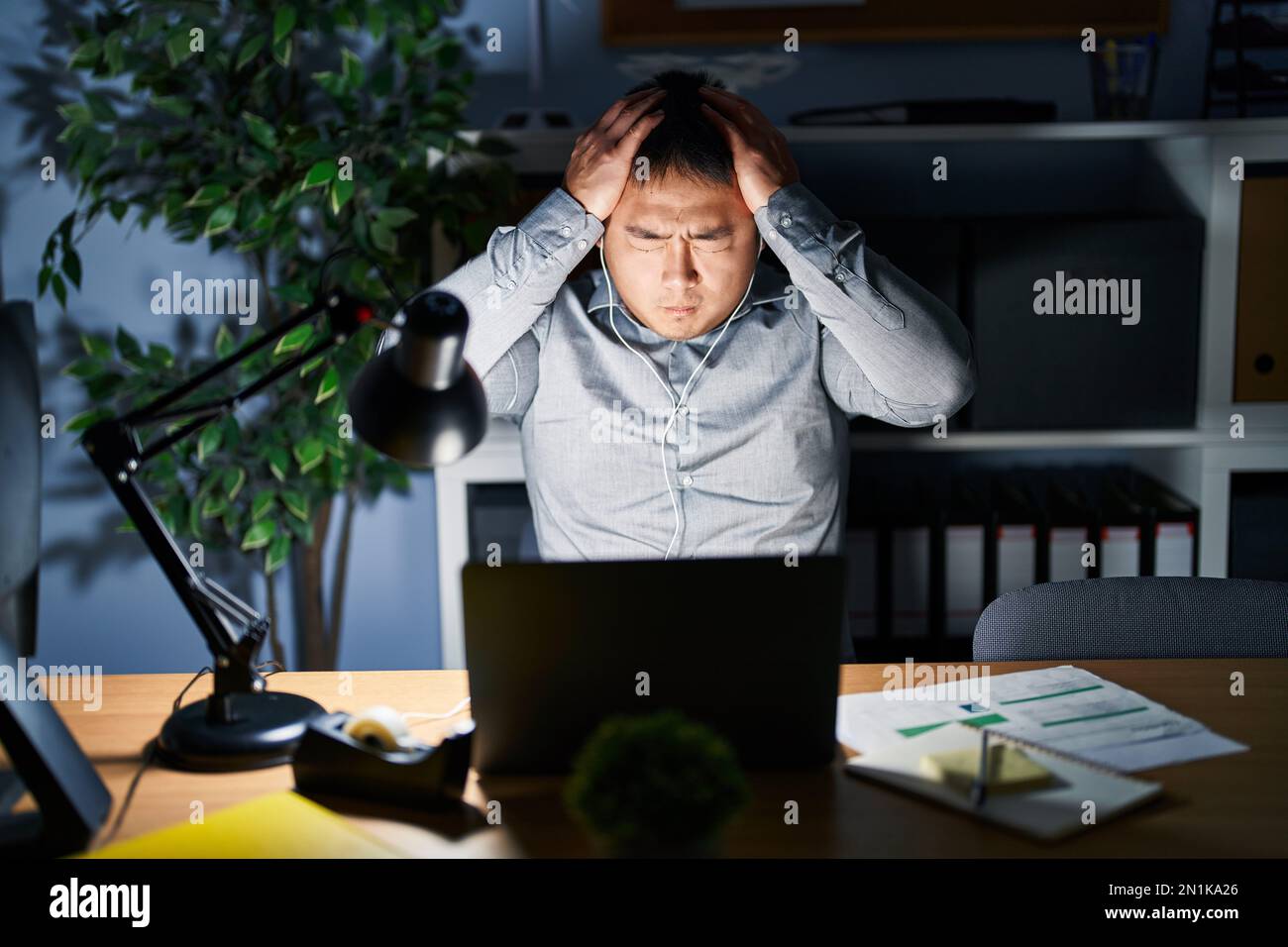 Young chinese man working using computer laptop at night suffering from ...