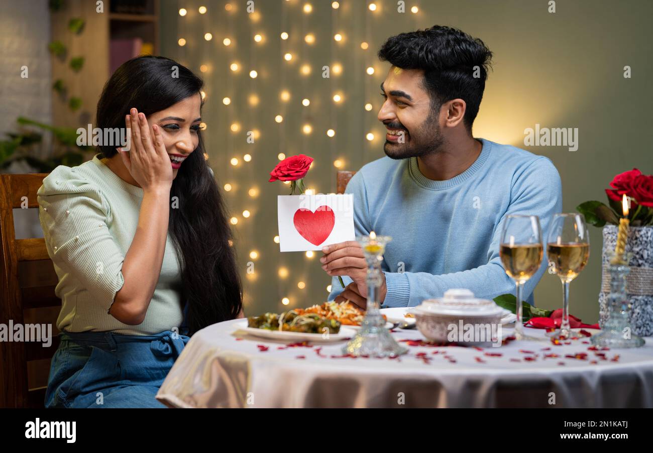 Happy young man proposing excited girl with rose and greetings during ...
