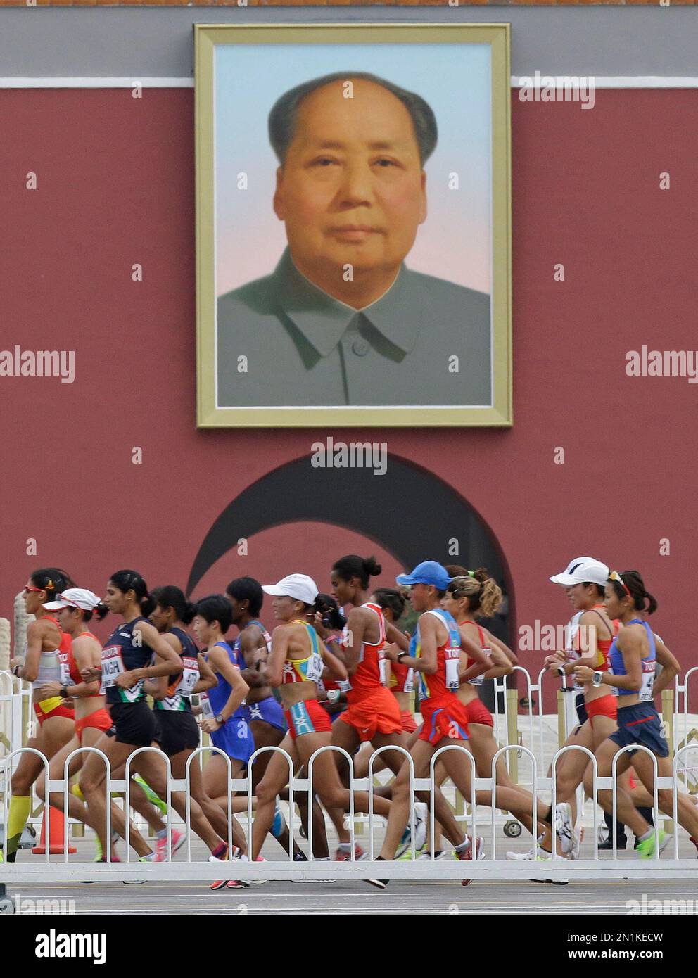 Competitors in the women's marathon race past an image of former ...