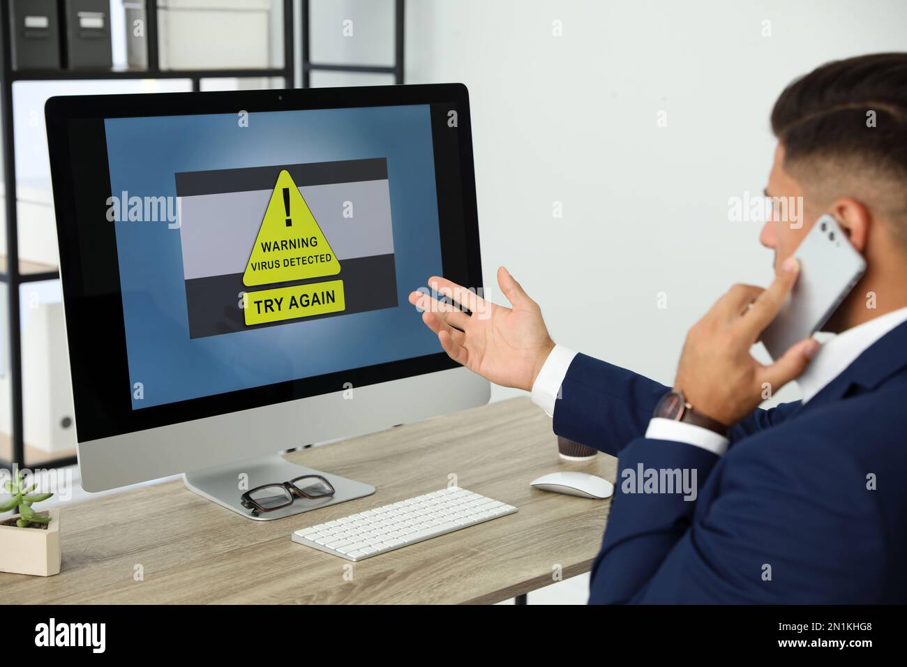 Office worker in front of computer with warning about virus attack on ...
