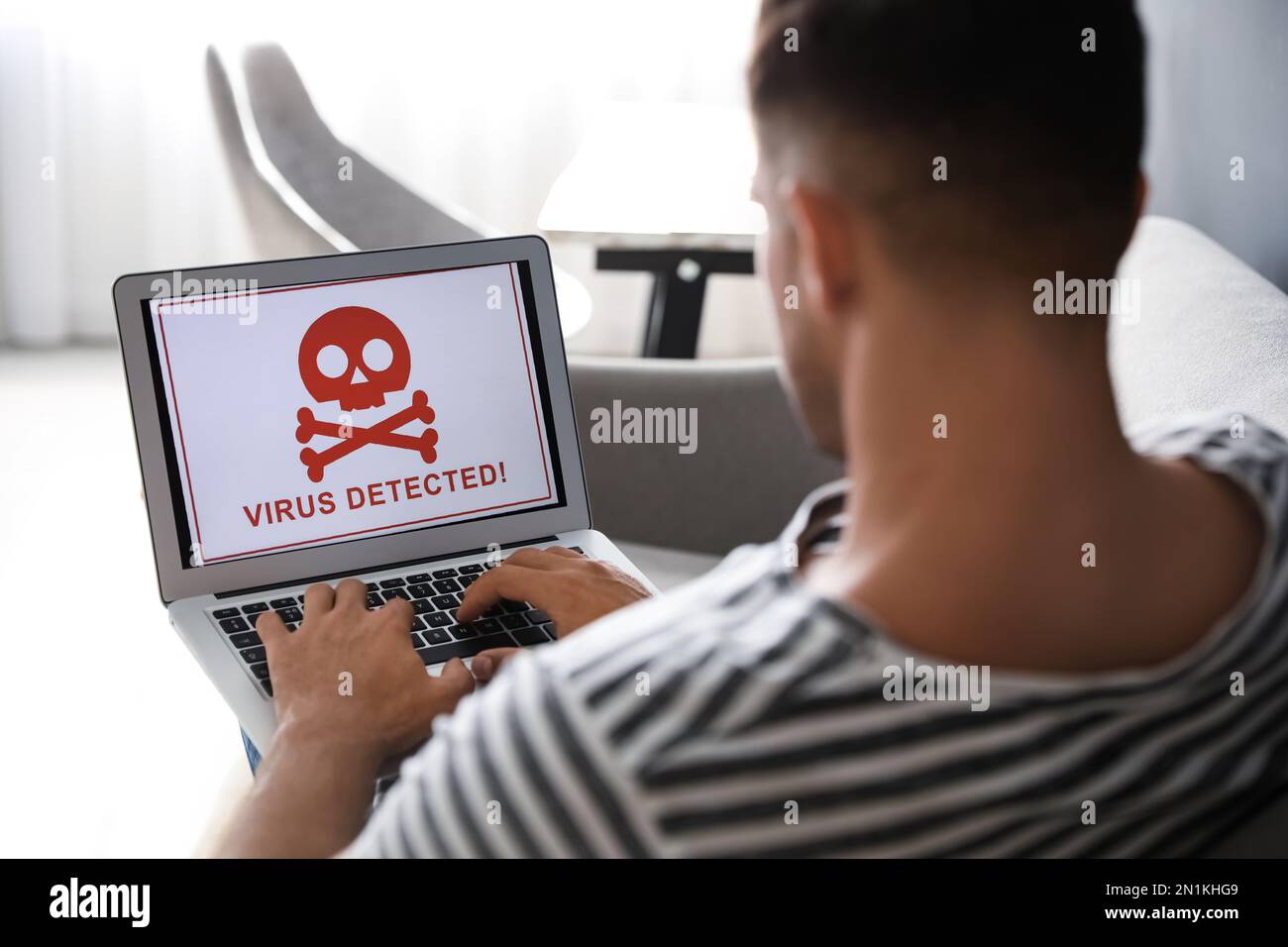 Man using laptop with warning about virus attack at home Stock Photo ...