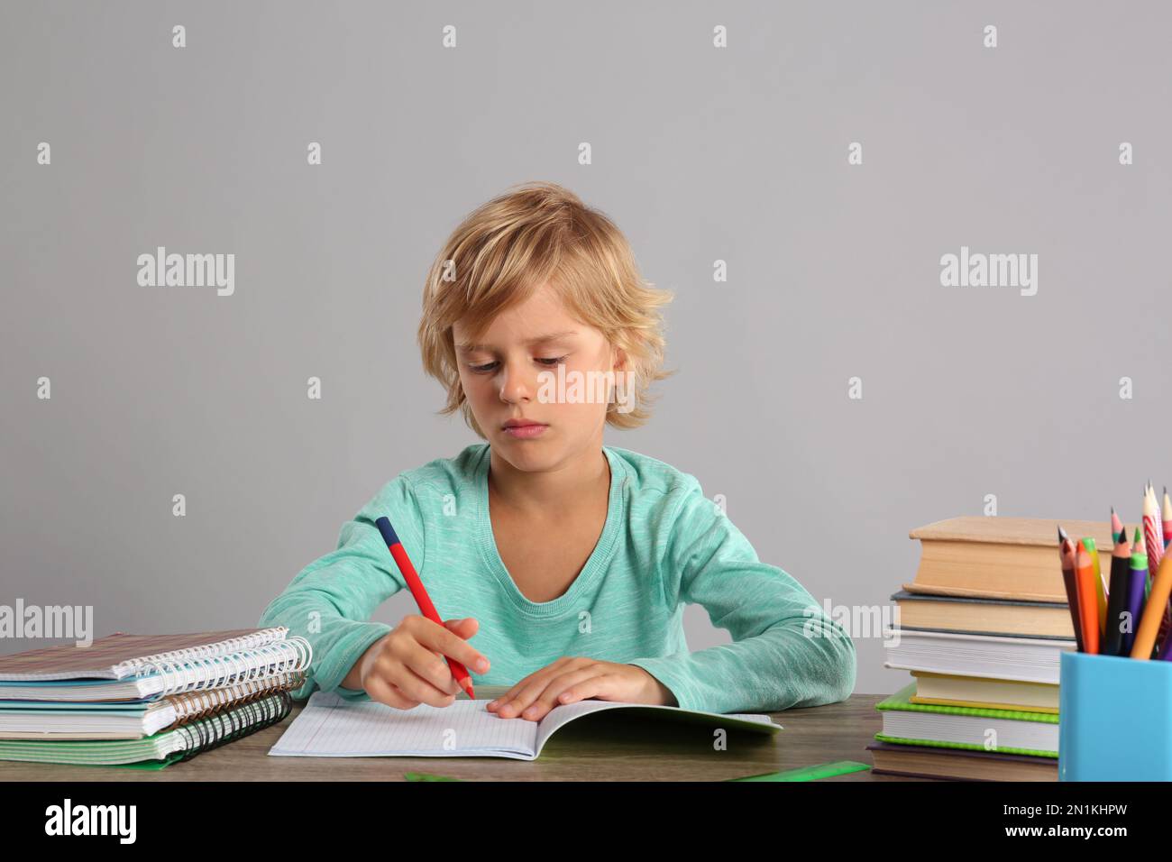 Little boy doing homework at table on grey background Stock Photo - Alamy