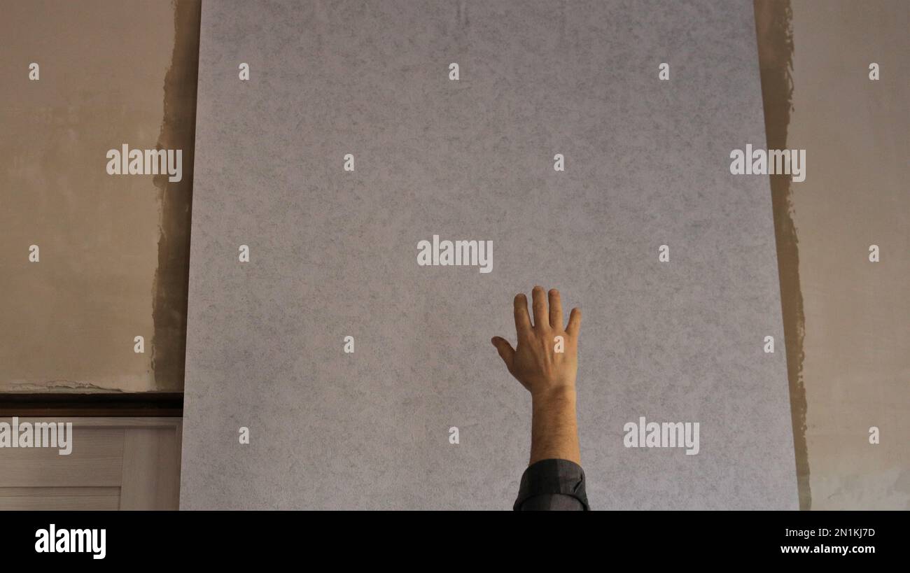outstretched male hand against the background of a room wall with a ...