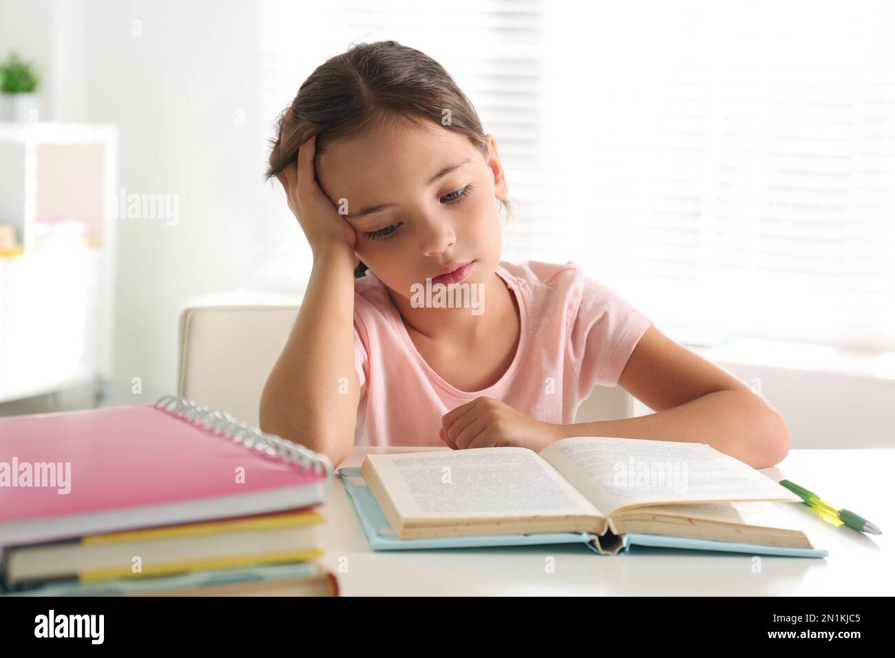 Sad little girl doing homework at table indoors Stock Photo - Alamy