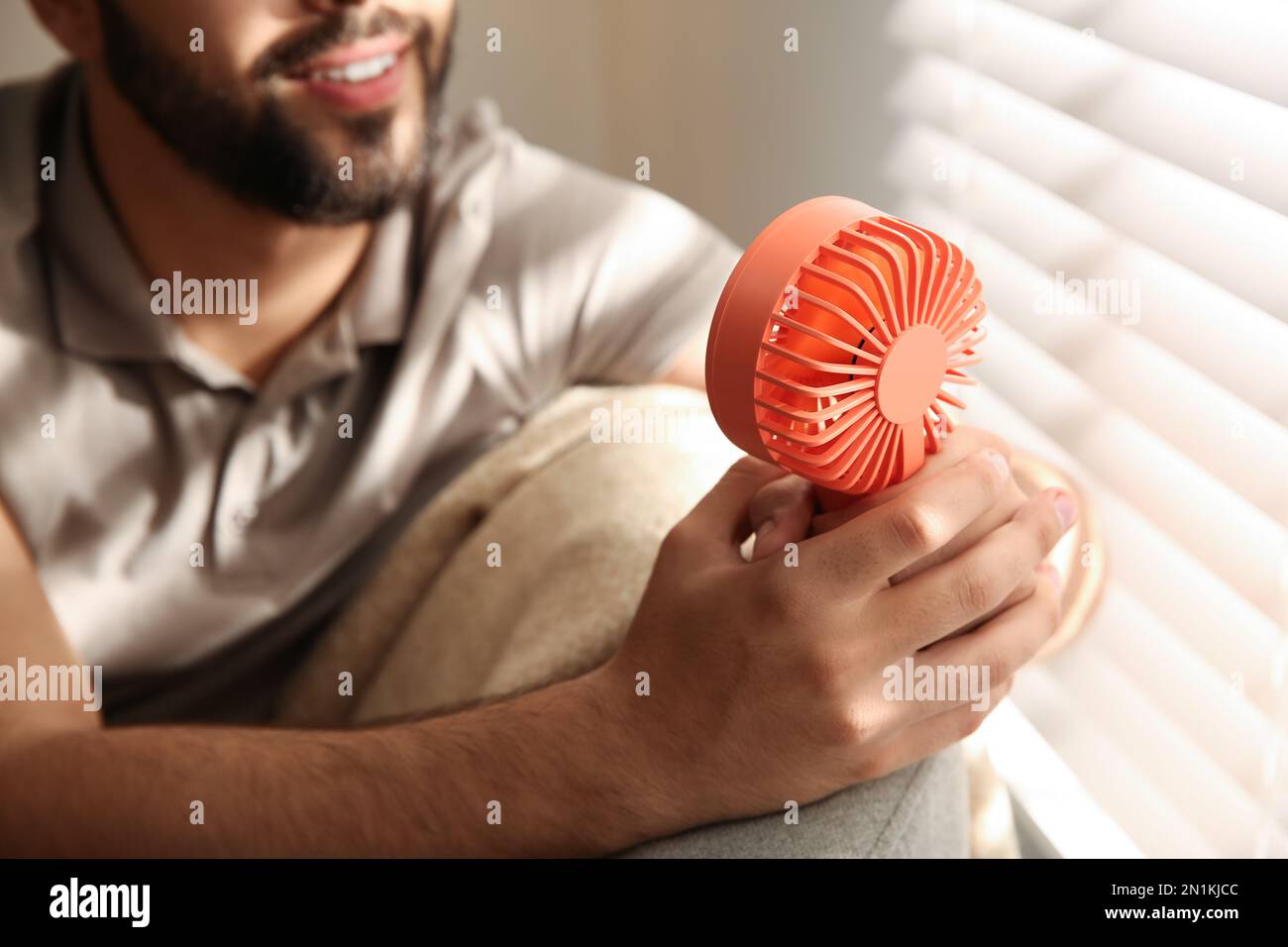 Man enjoying air flow from portable fan at home, closeup. Summer heat ...