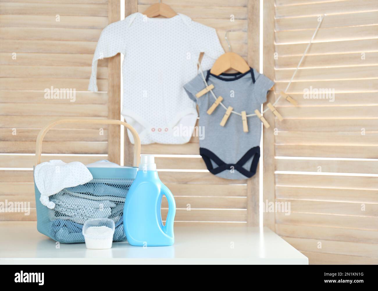 Basket with baby laundry, bottle of detergent and washing powder on ...