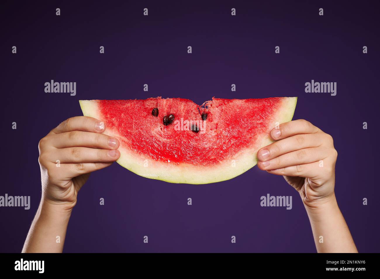 Child holding watermelon on purple background, closeup of hands Stock ...