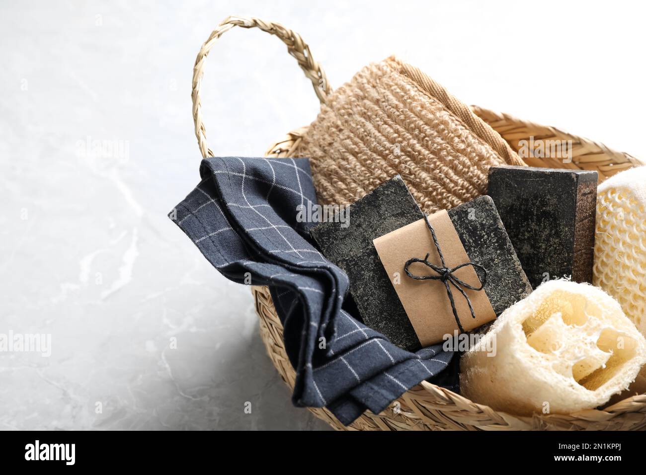 Natural tar soap in wicker basket on light grey table. Space for text ...