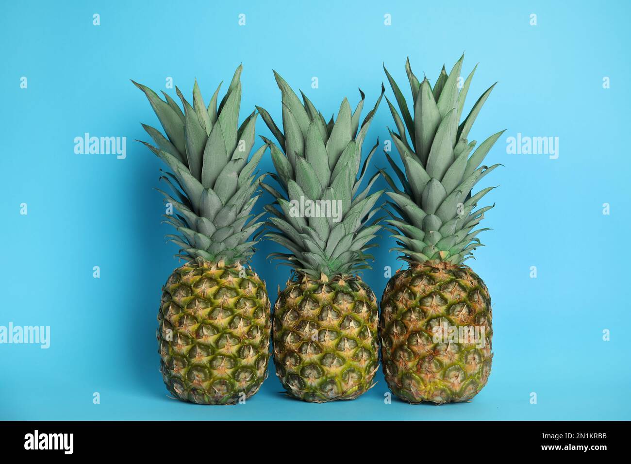 Ripe juicy pineapples on light blue background Stock Photo - Alamy