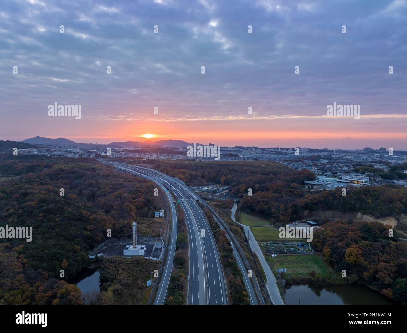 First rays of sun light sky over curved road through landscape Stock ...