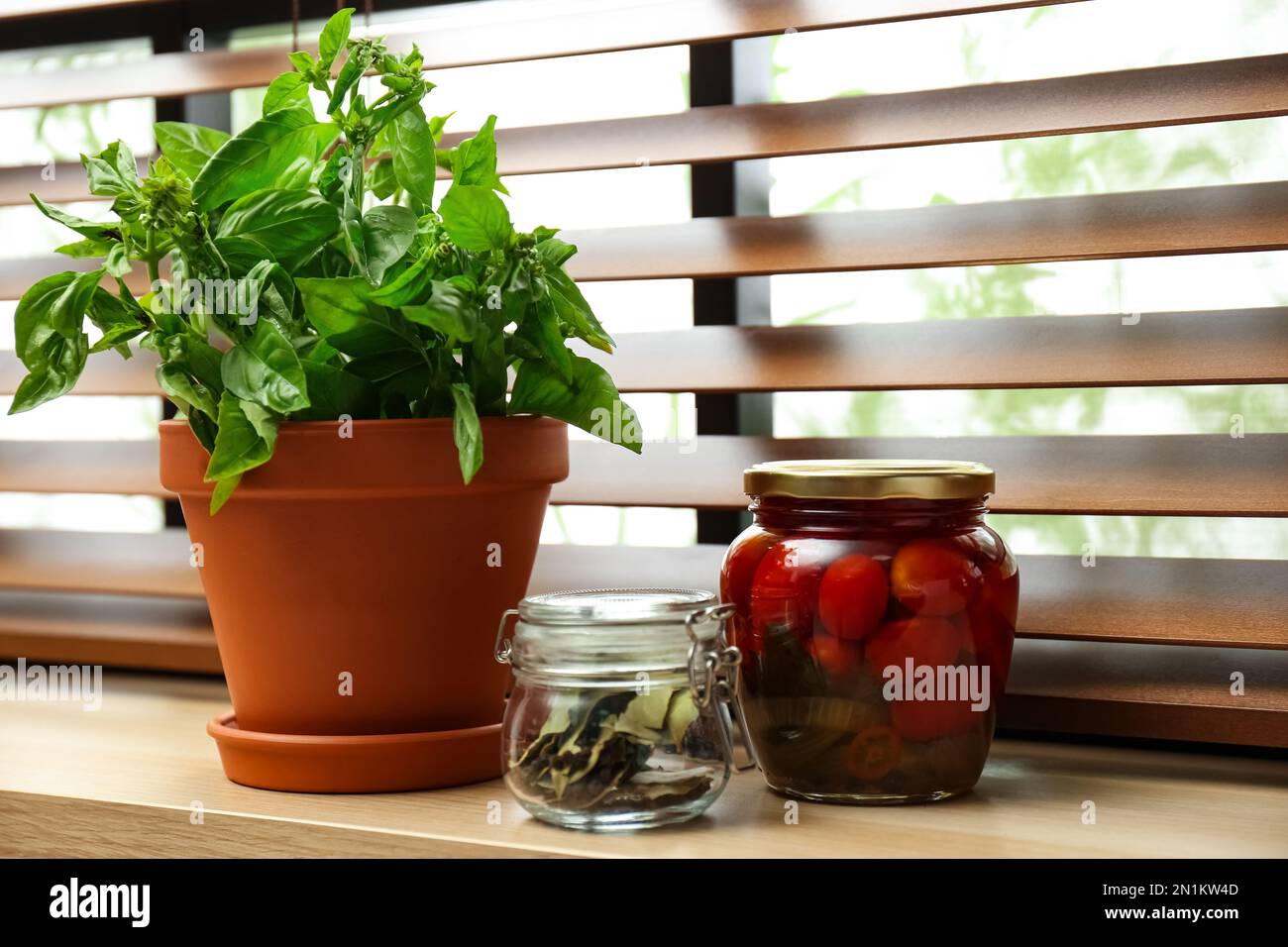 Green basil, pickled tomatoes and spices on window sill indoors Stock ...