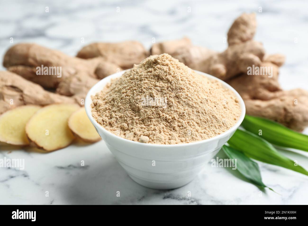 Dry ginger powder, fresh root and leaves on white marble table Stock ...
