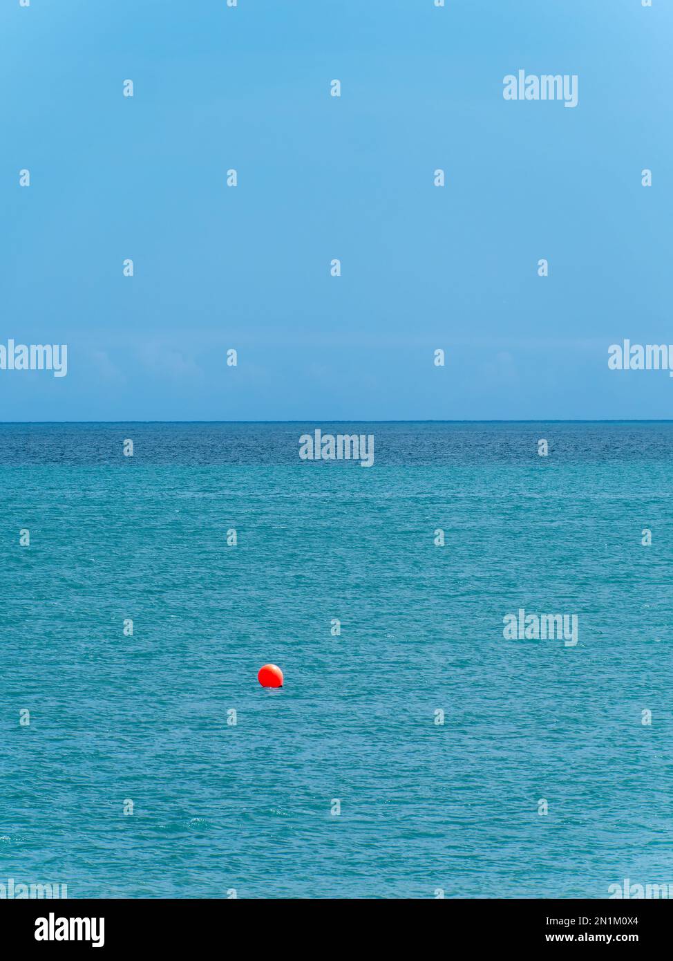 Clear sky over a blue sea. An orange buoy on the surface of the water ...