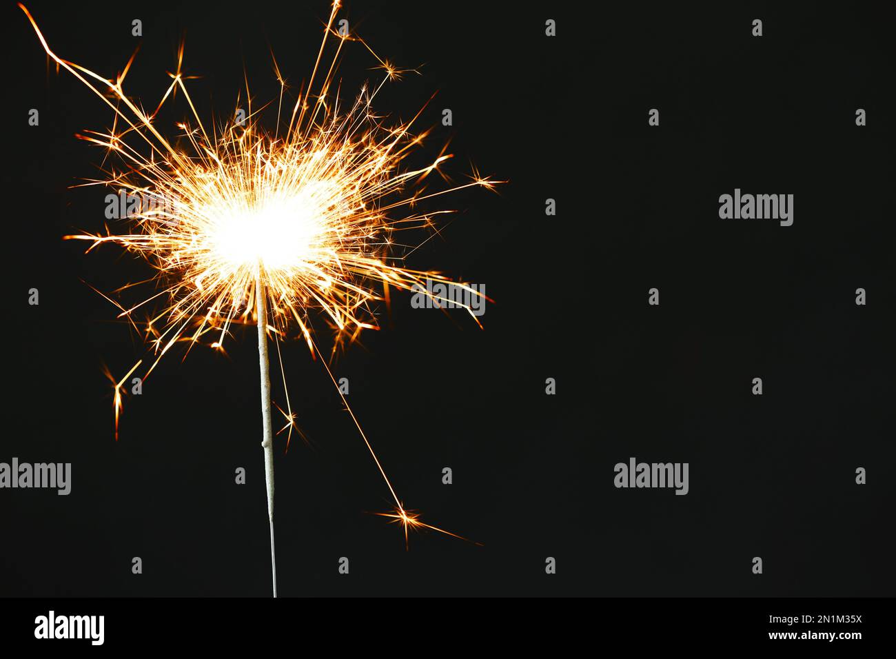 Bright burning sparkler on black background, closeup. Space for text ...
