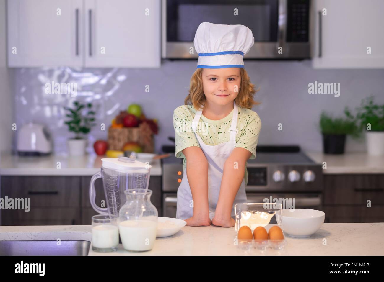 Funny child stand at kitchen table have fun baking, doing bakery ...