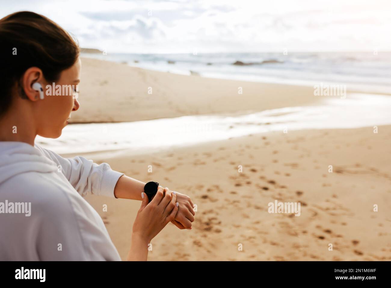 Athletic young woman tracking her outdoor activity, looking at ...